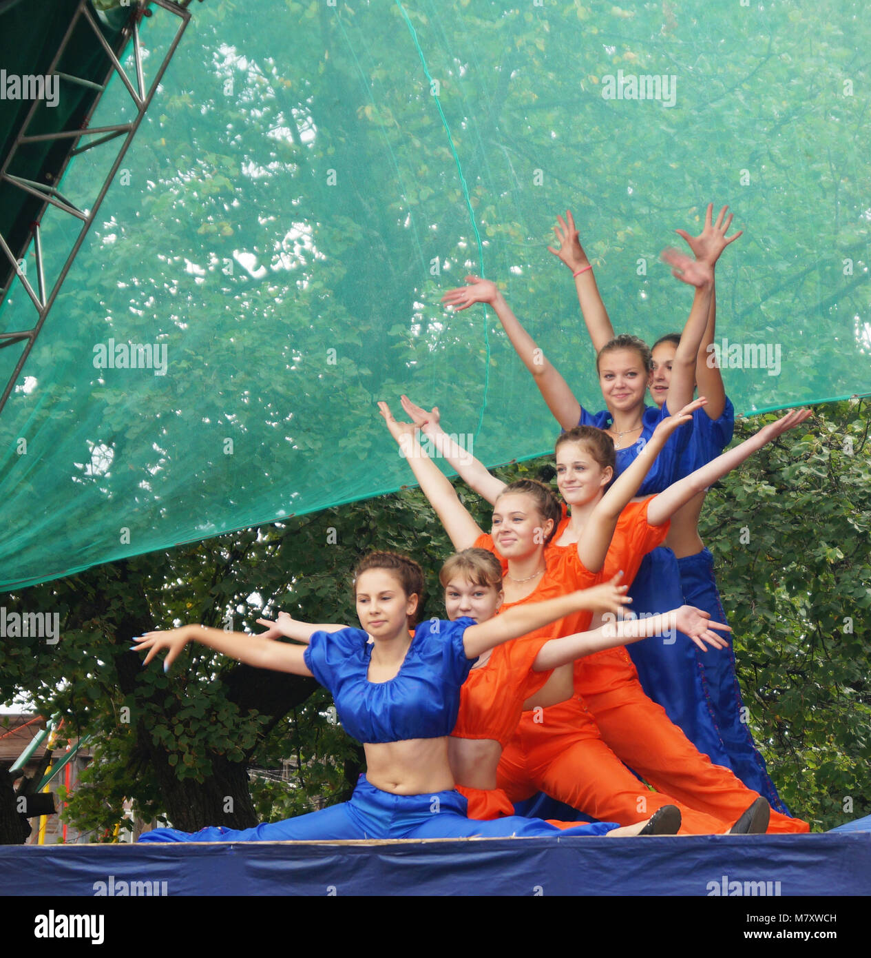 Young girls in bright suit dance and show acrobatic stunts on scene ...