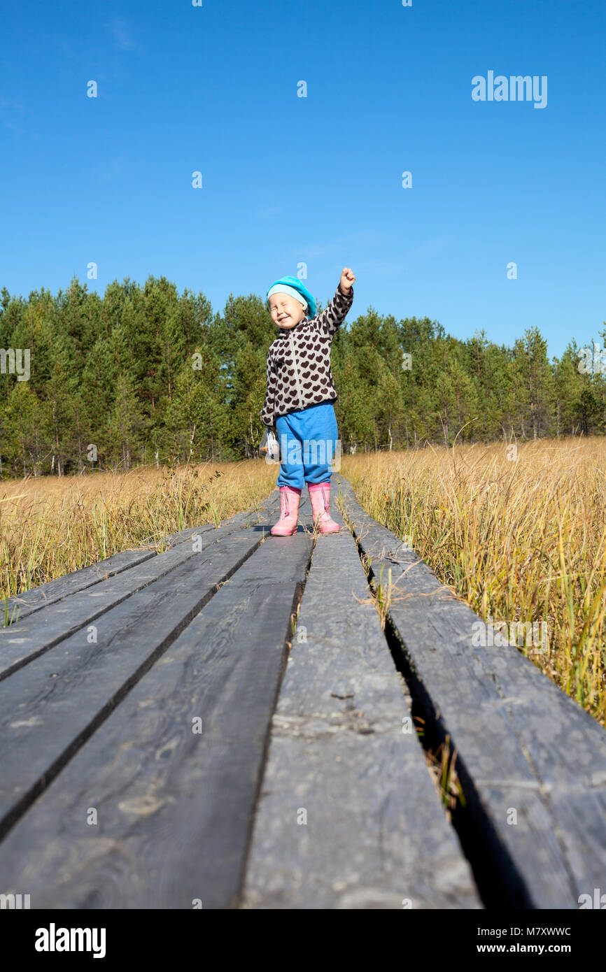 Little child with arm up and narrowing eyes standing on background on ...