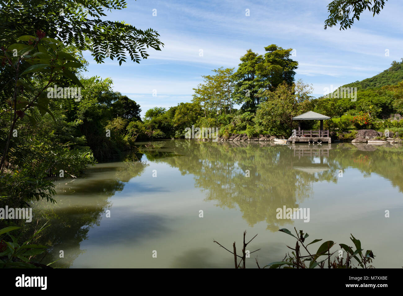 Pavilion rest area and mountain lake surrounded by forest, reflected in ...