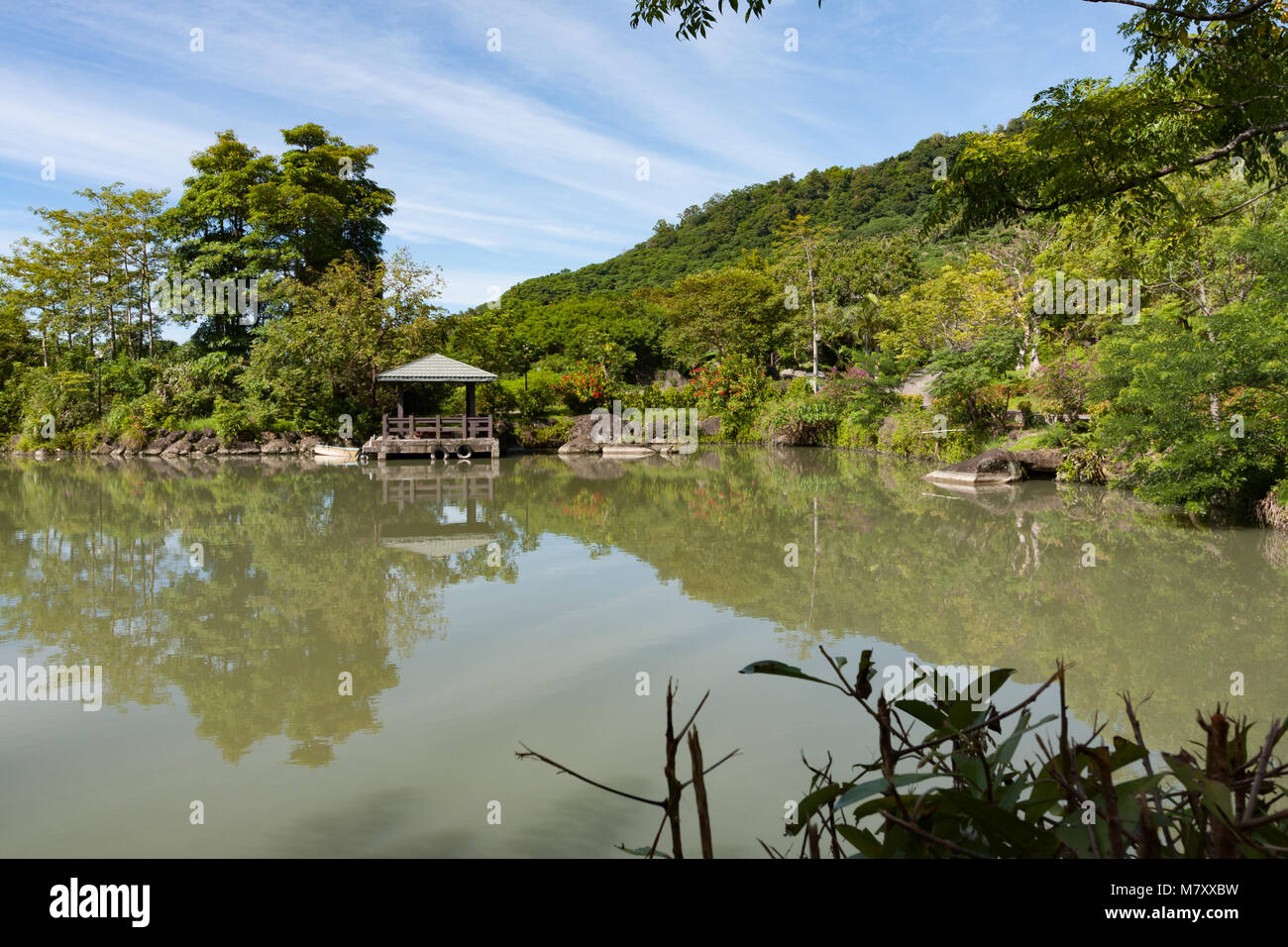 Pavilion rest area and mountain lake surrounded by forest, reflected in ...