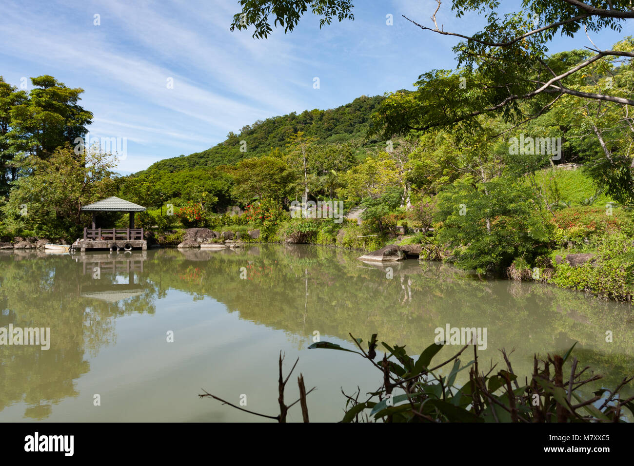 Pavilion rest area and mountain lake surrounded by forest, reflected in ...