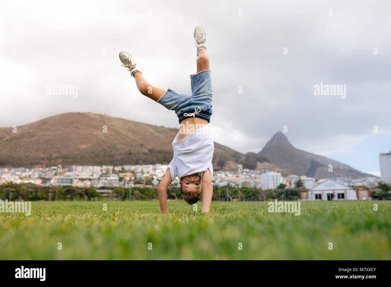 Boy balancing on hands in upside down position in a ground. Boy playing ...