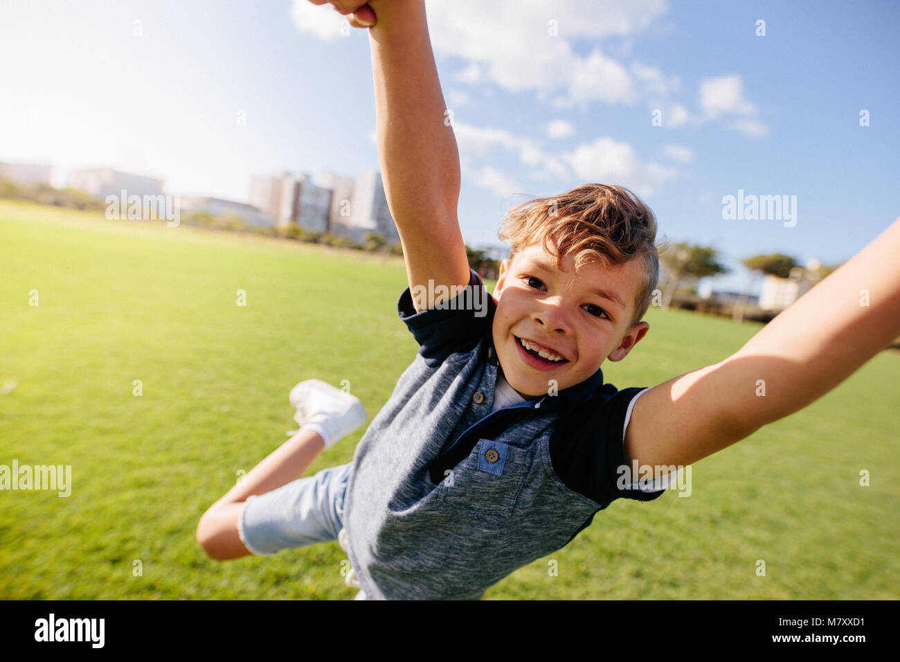 Close up of a boy jumping in air at a park. Cheerful boy enjoys being ...