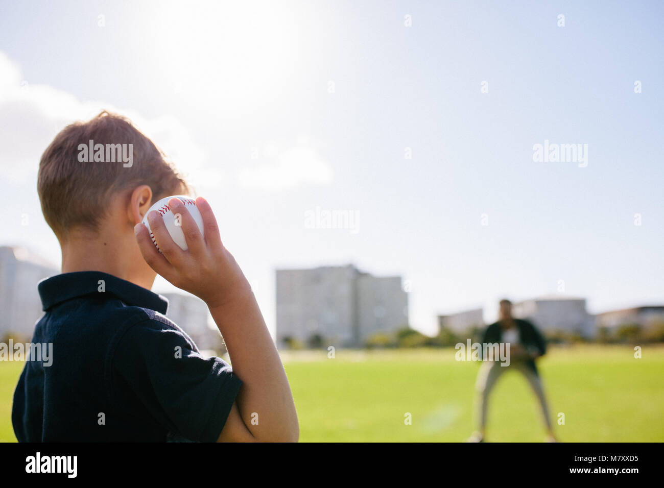 Rear view close up of a boy throwing baseball at a man in a ground. Boy ...