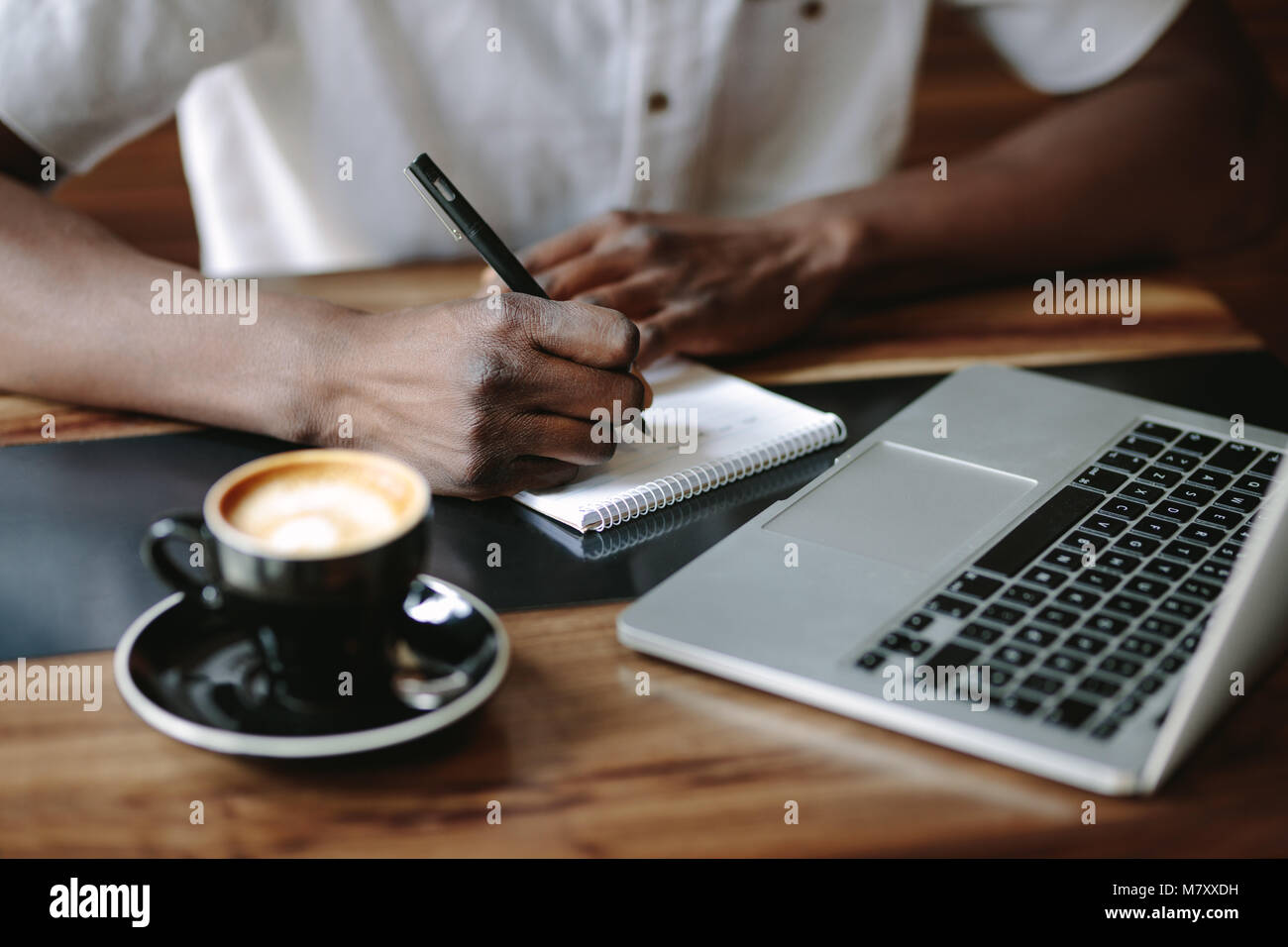 Freelancer writing notes sitting at a coffee table. Cropped shot of man ...