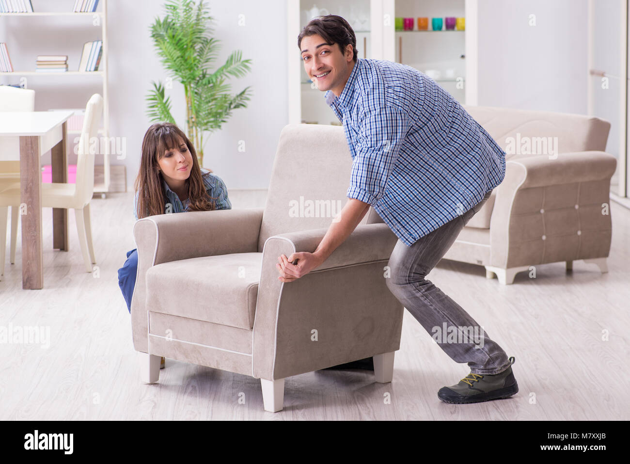 Man moving armchair in the living room Stock Photo - Alamy