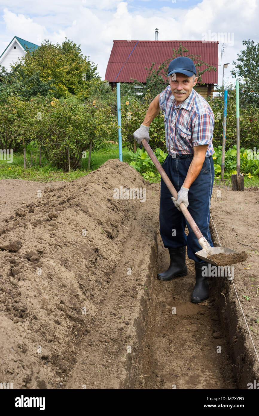 Farmer digging the earth to build deep bed of in the garden Stock Photo ...