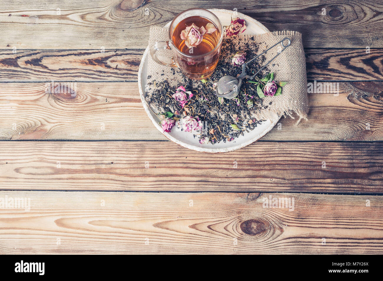 Rose buds tea, tea cup, strainer and glass jar with rosebuds. Selective ...