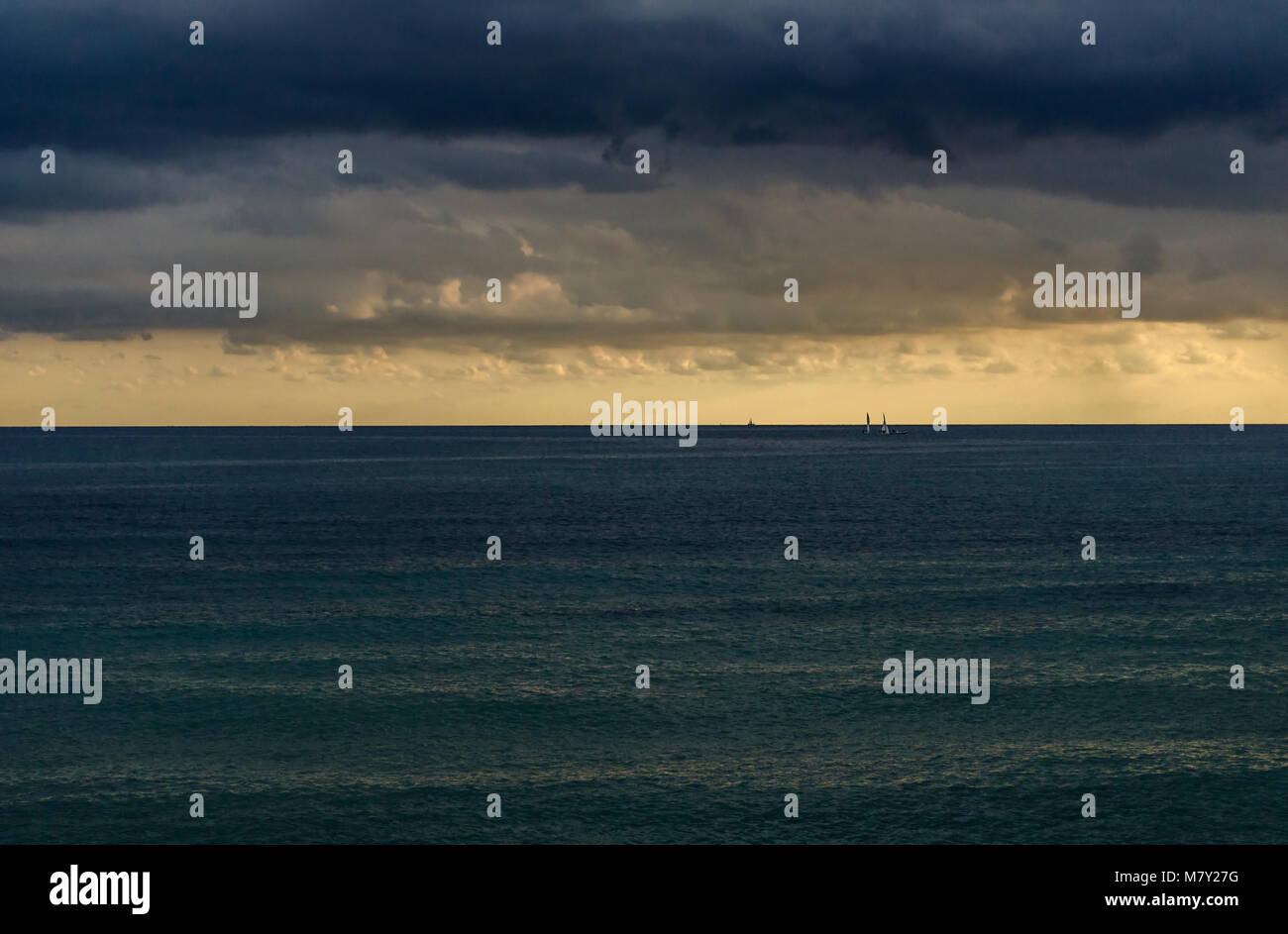 blue sunset with distant ships on the horizon Stock Photo - Alamy