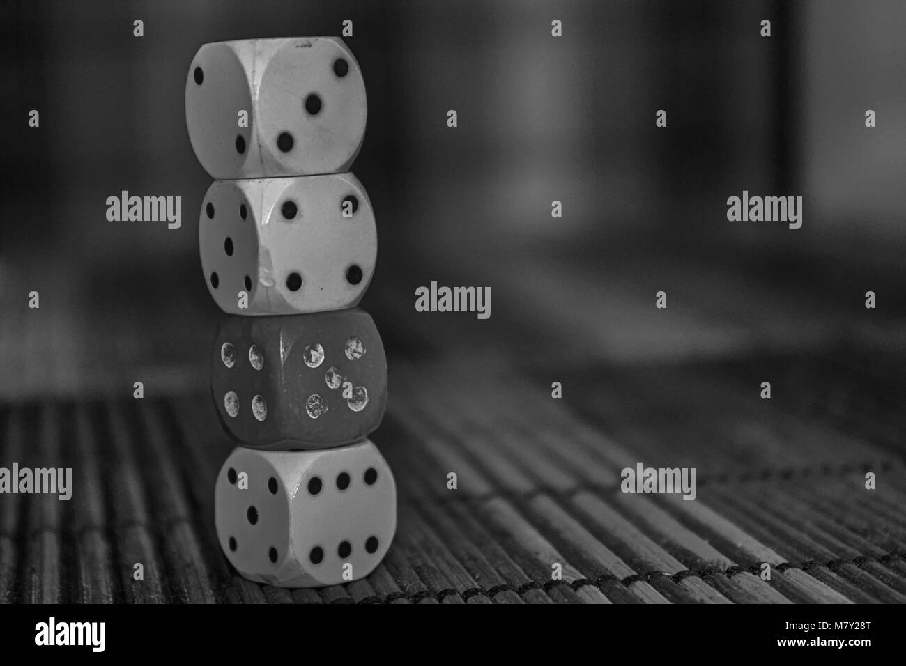 Monochrome Stack of three white plastic dices and one red dice on brown ...