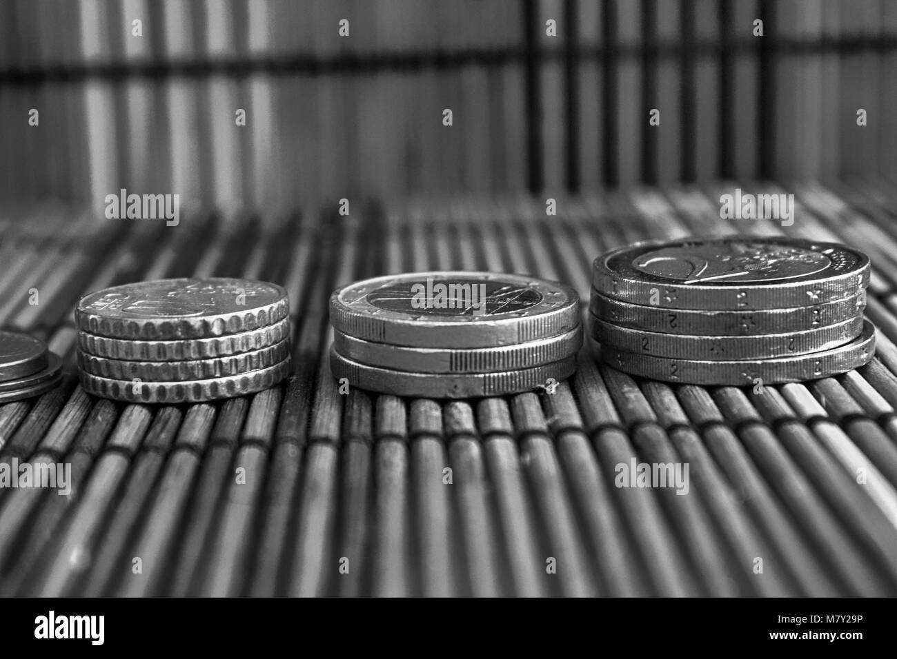 Pile of euro coins, like a tower lies on wooden bamboo table background ...