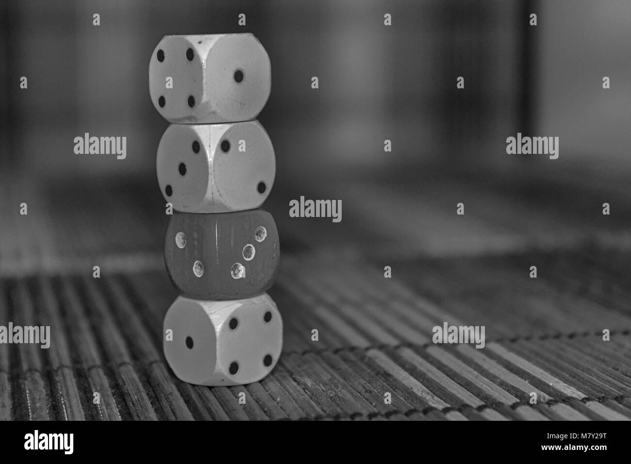 Monochrome Stack of three white plastic dices and one red dice on brown ...