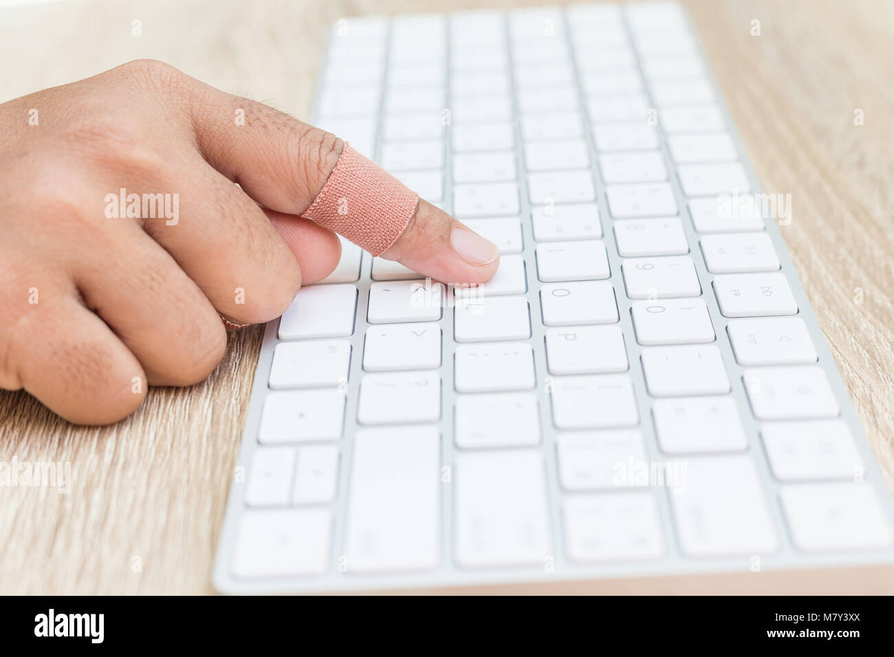 Close up hand with injury on finger using white computer keyboard on ...