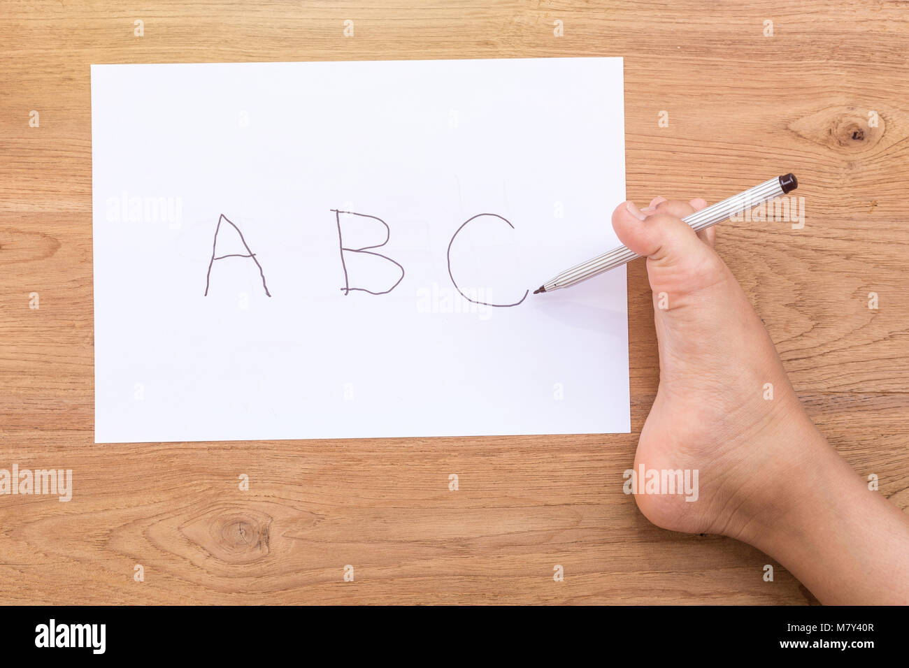 Word "ABC" in white paper writing by right foot of disabled people on ...