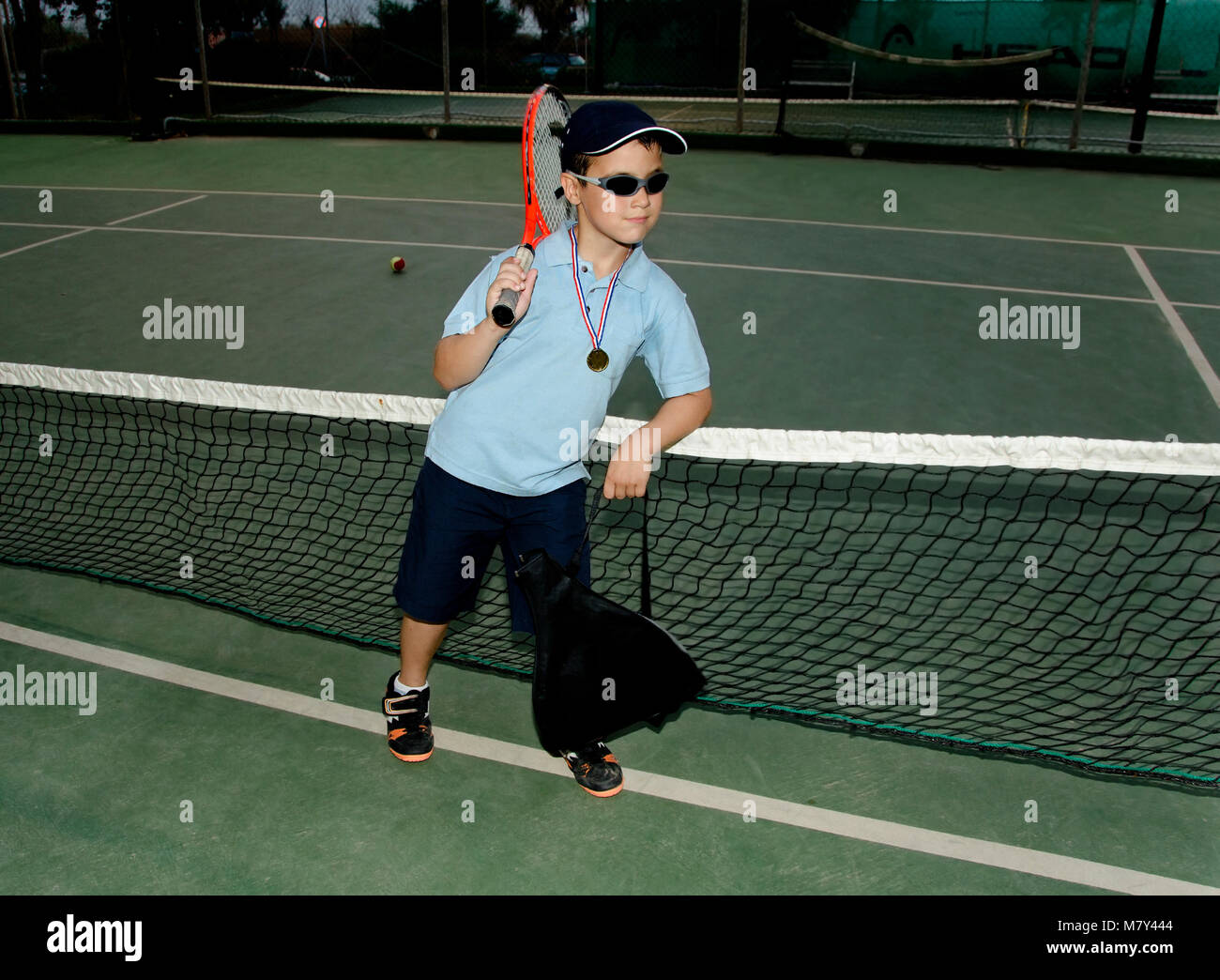 Boy with racket and sunglasses posing for a photo after a tennis game ...