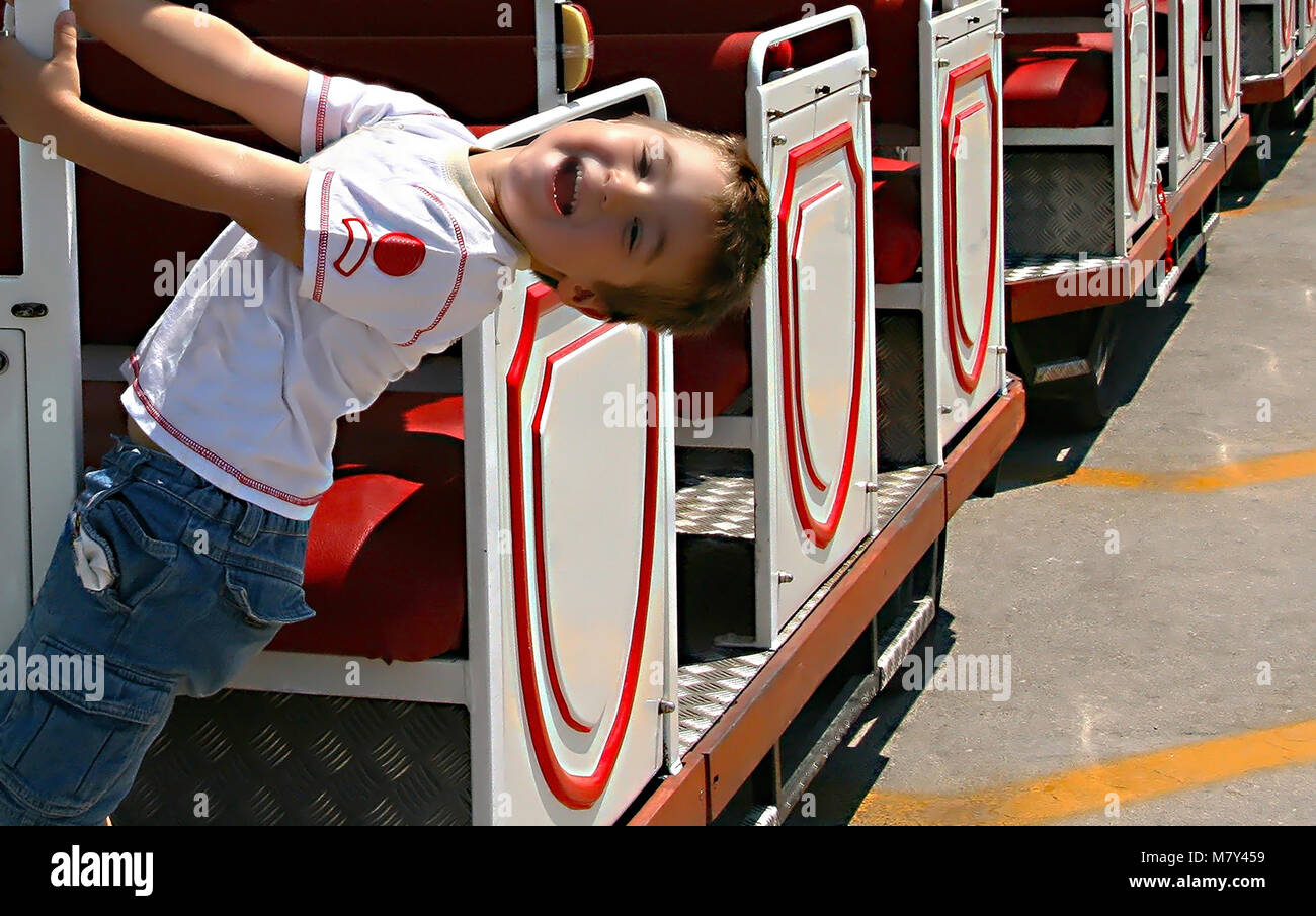 Little happy boy playing and hanging on the side of sightseeing train ...