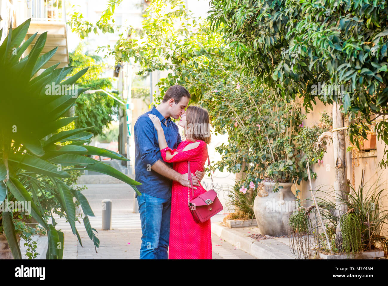 Romantic young couple in bright red and blue clothes embracing on the ...