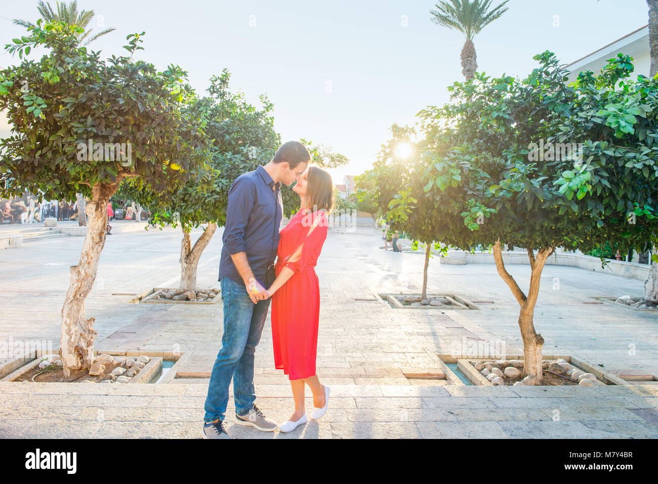 Romantic young couple in bright red and blue clothes holding hands and ...