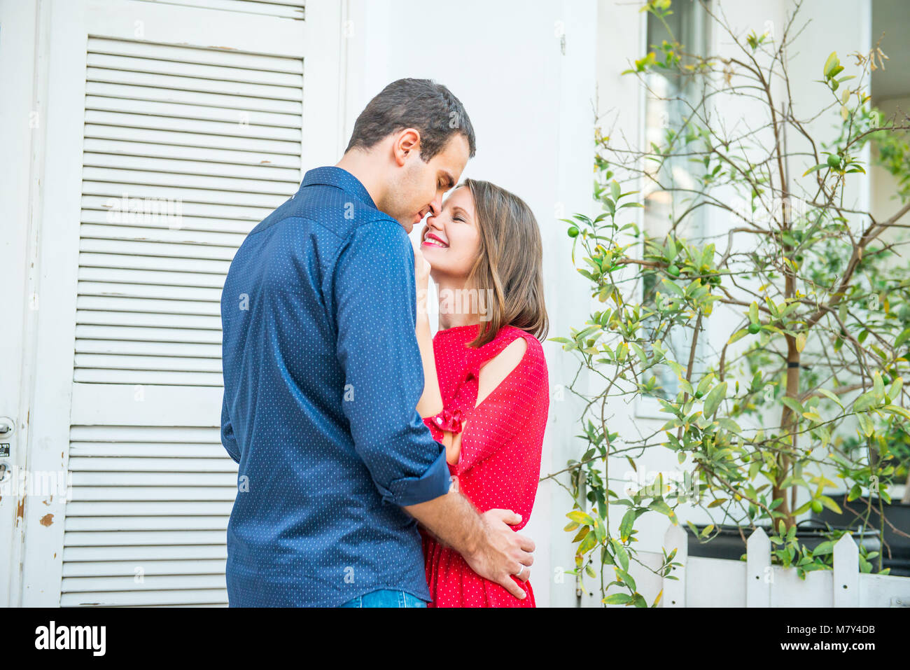 Romantic young couple in bright red and blue clothes embracing on the ...