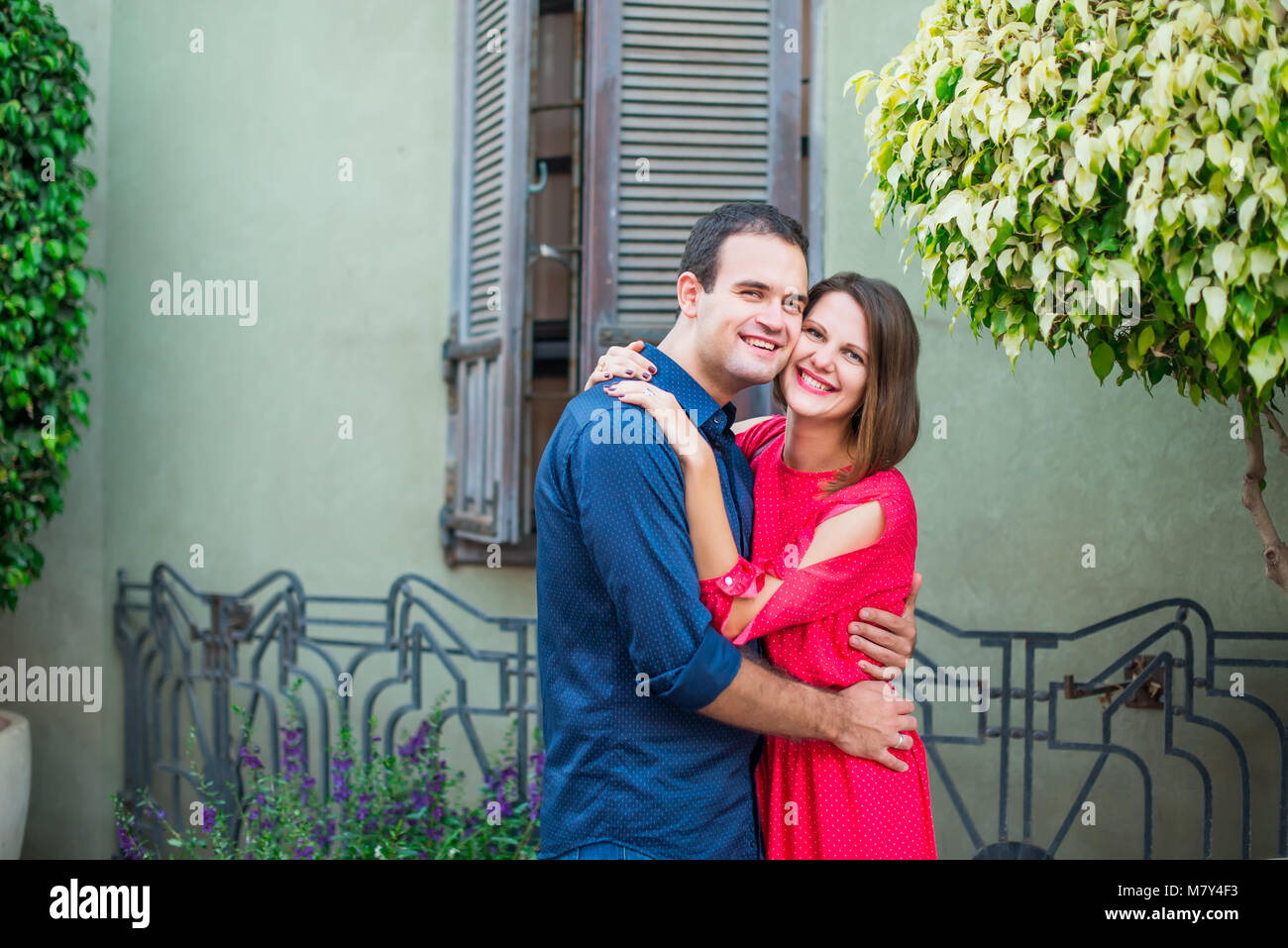 Romantic young couple in bright red and blue clothes embracing and ...