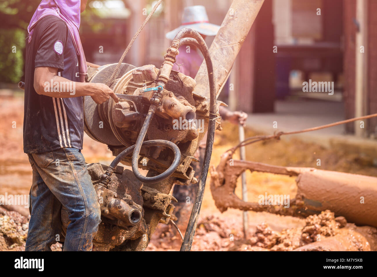 Asian worker installing wet-process bored pile for outside public ...