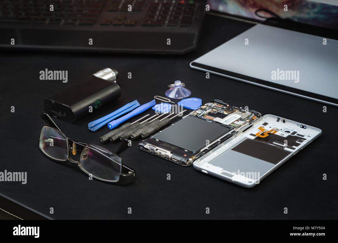 Workplace of the repairman with the disassembled smartphone, vape ...