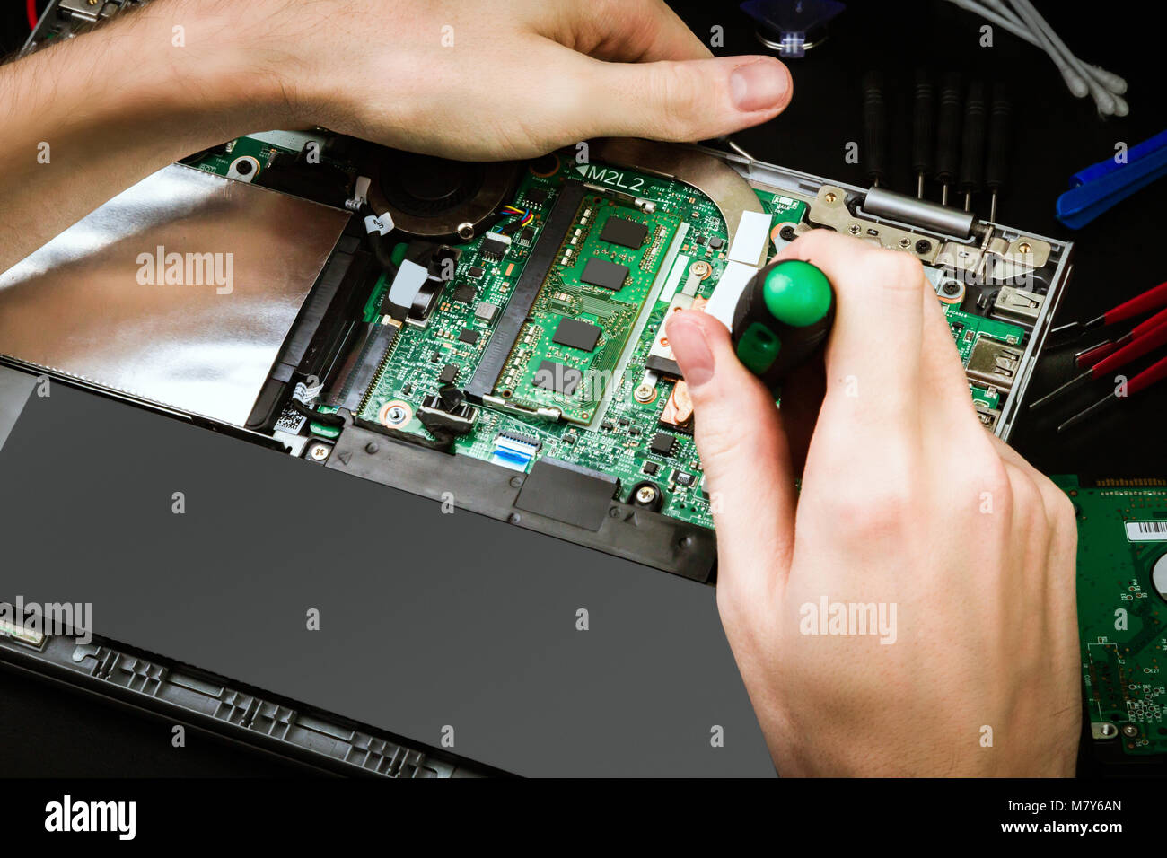 Repair a broken laptop with details and special tools on a black desk ...