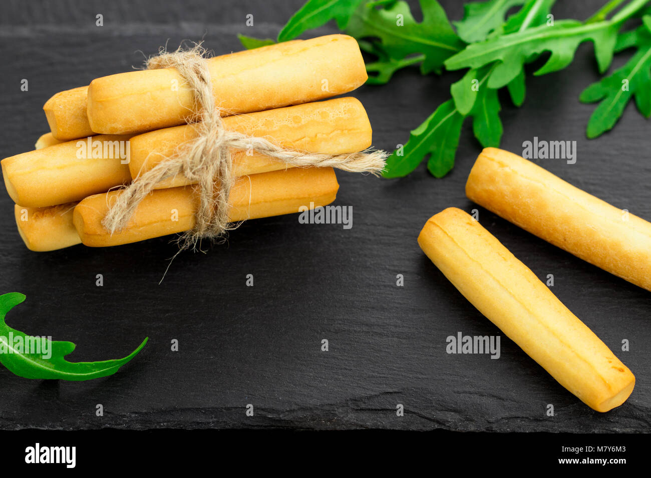 Crispy bread sticks with arugula, bread sticks on black stone ...