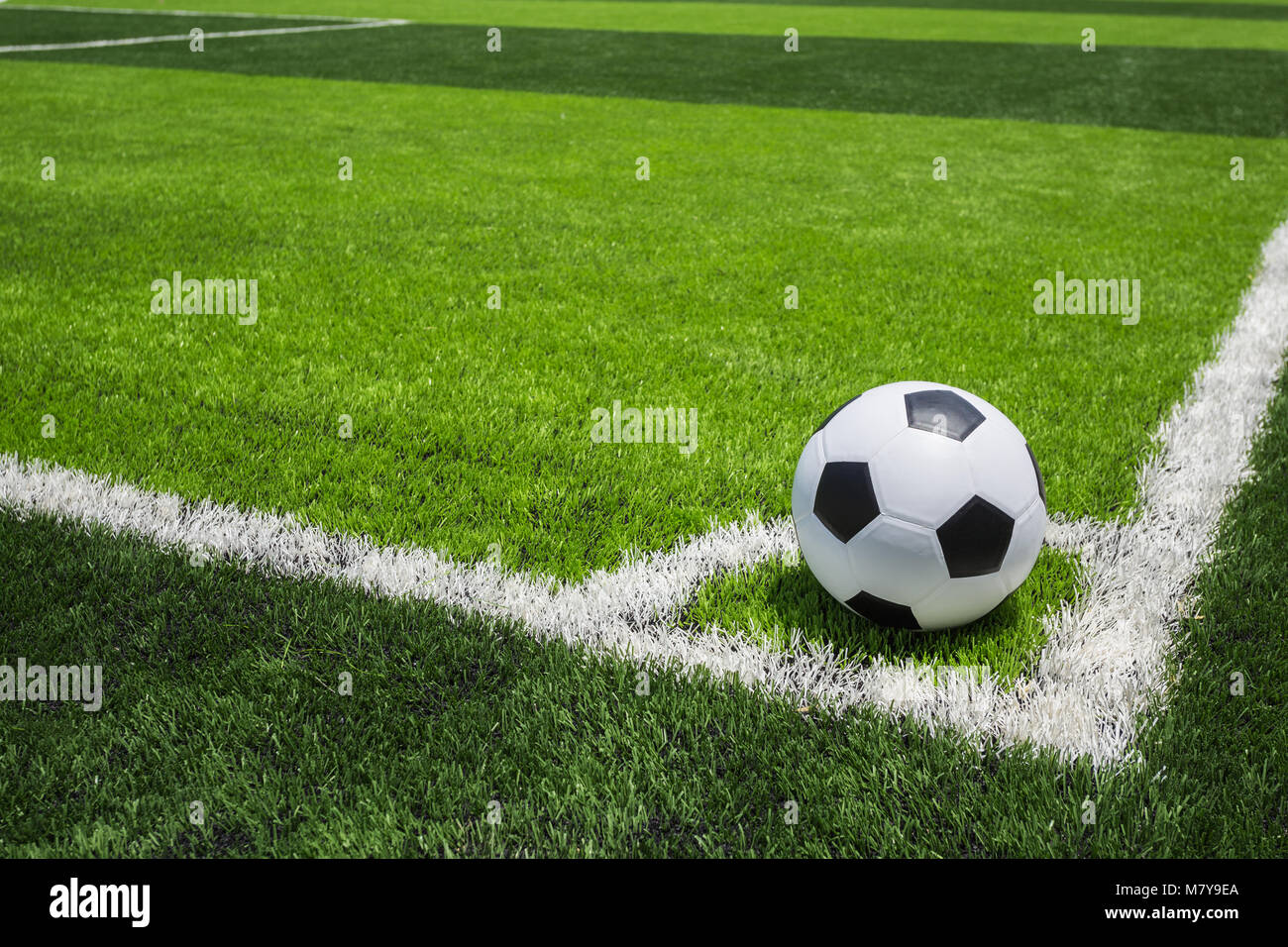 Classic soccer ball on artificial bright and dark green grass at public ...