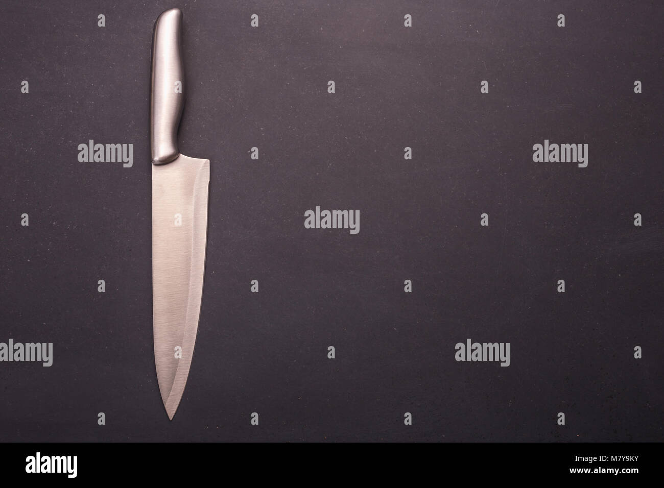 New stainless steel cooking knife. Studio shot on black stone ...