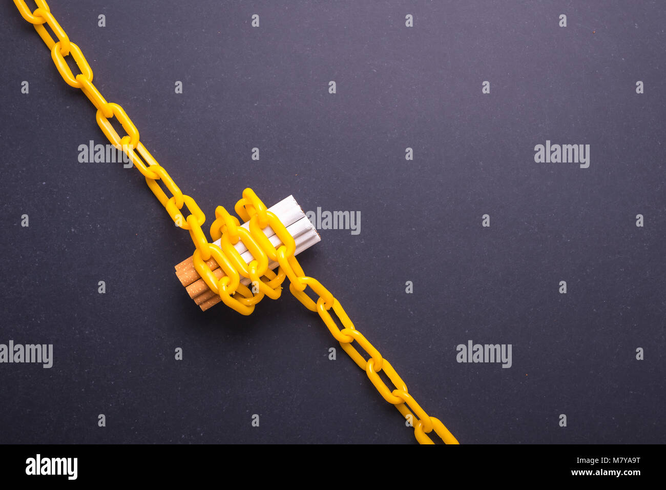 Stop smoking concept. Yellow chain locked around cigarette. Top view on ...