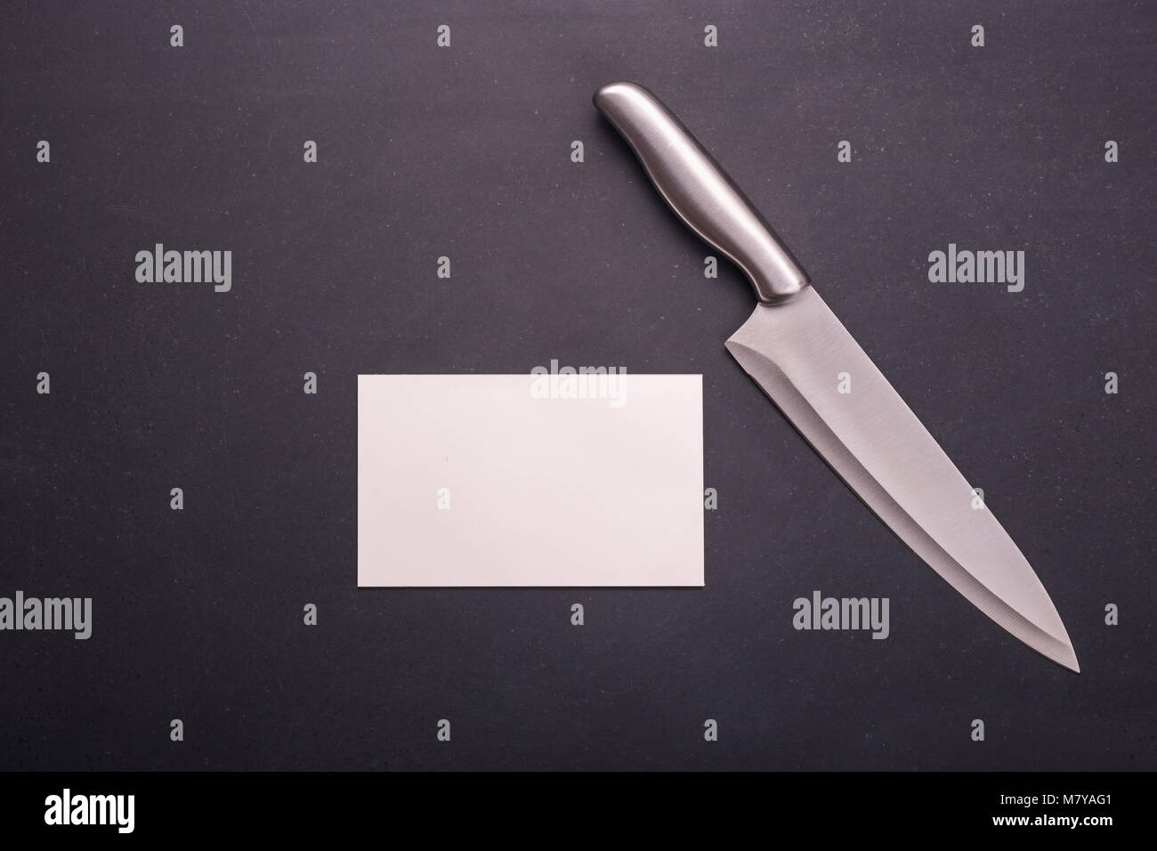 New stainless steel cooking knife on black stone background. Top view ...