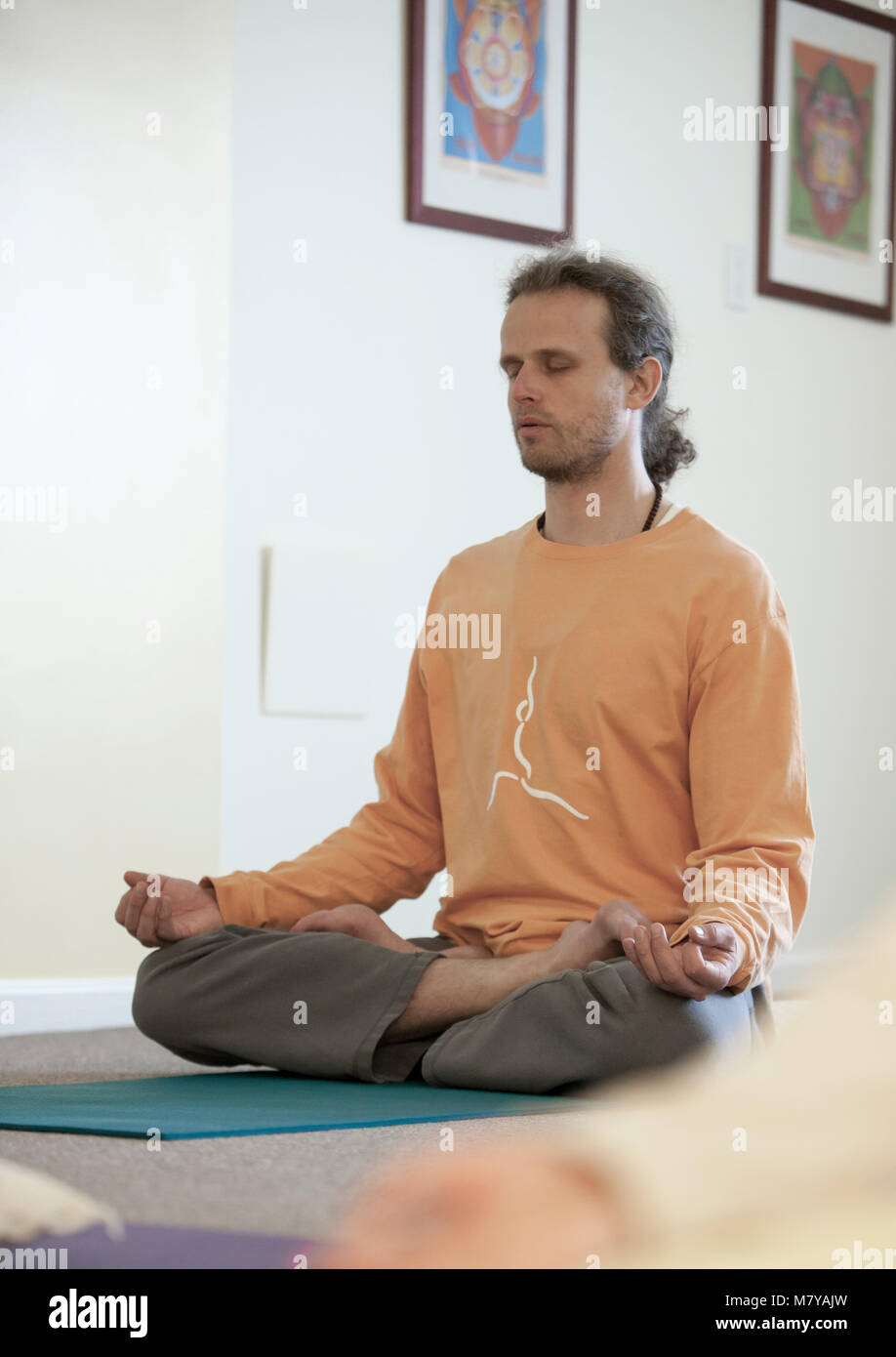 Young blonde man chanting om and meditating with straight back, crossed ...