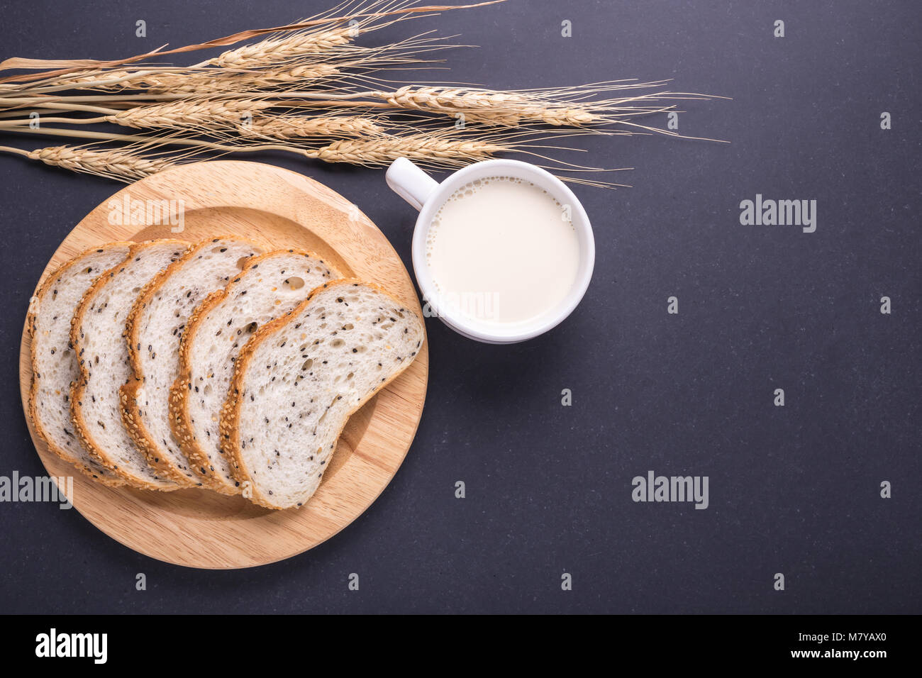 Slices of fresh white bread with sesame seeds on black stone table ...