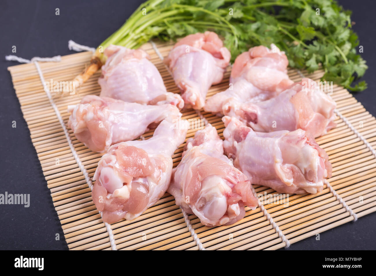 Fresh chicken wingstick and green vegetable on black stone table ...
