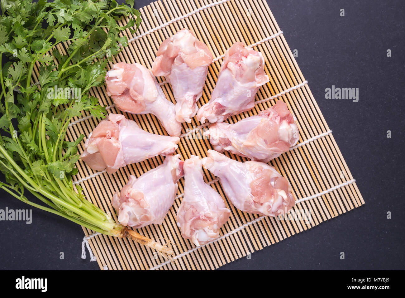 Fresh chicken wingstick and green vegetable on black stone table ...