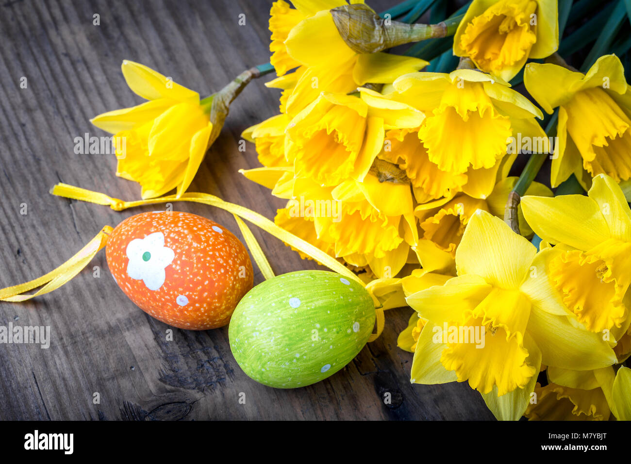 Bunch of daffodils on the wooden background with easter eggs for Easter ...