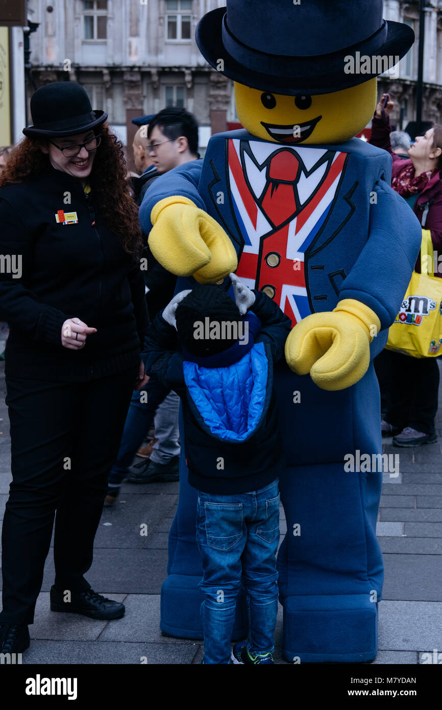 Man dressed in a Lego Man costume and a shop attendee interact with a ...