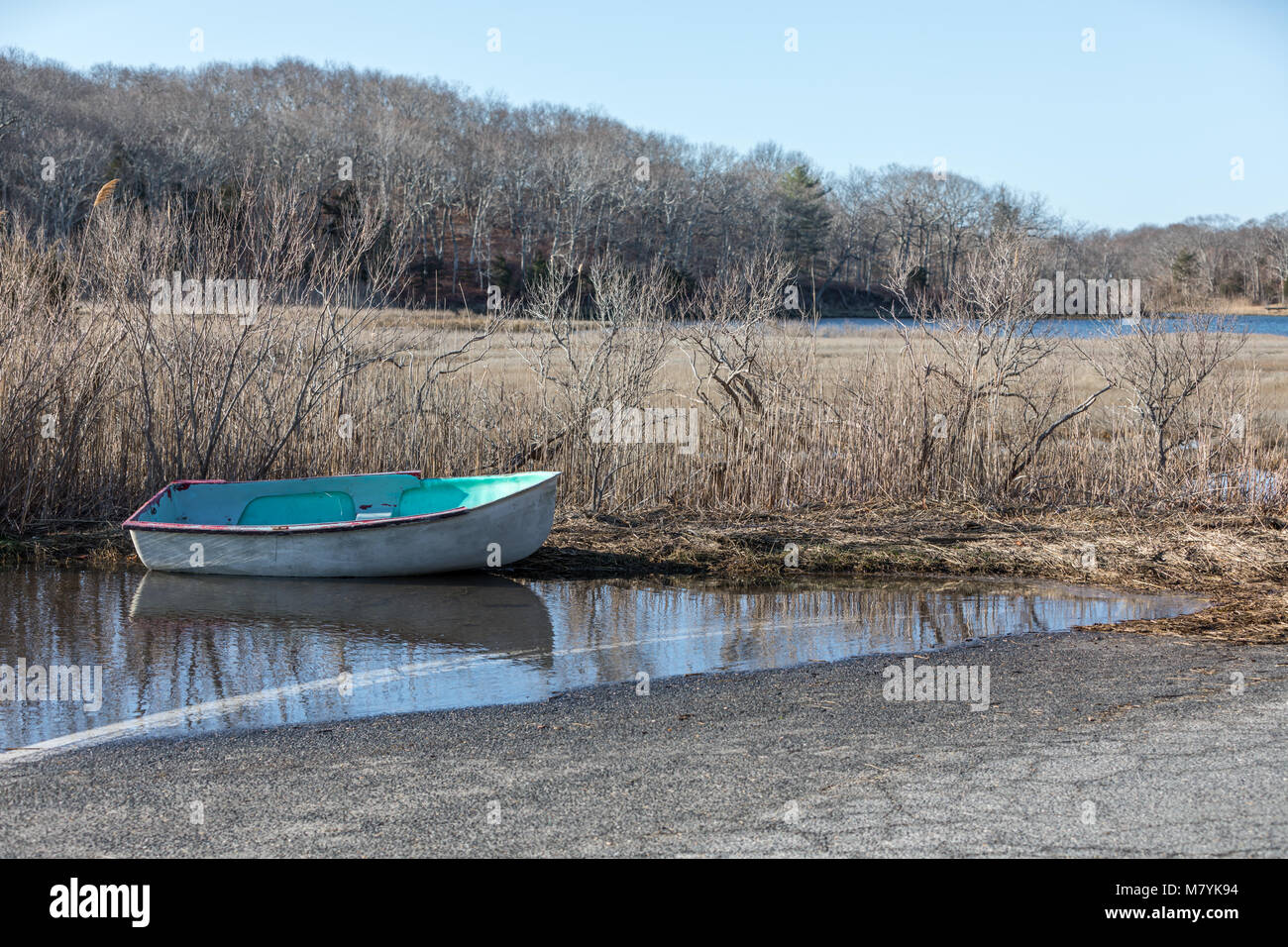a small colorful row boat sitting in shallow water, having been washed ...