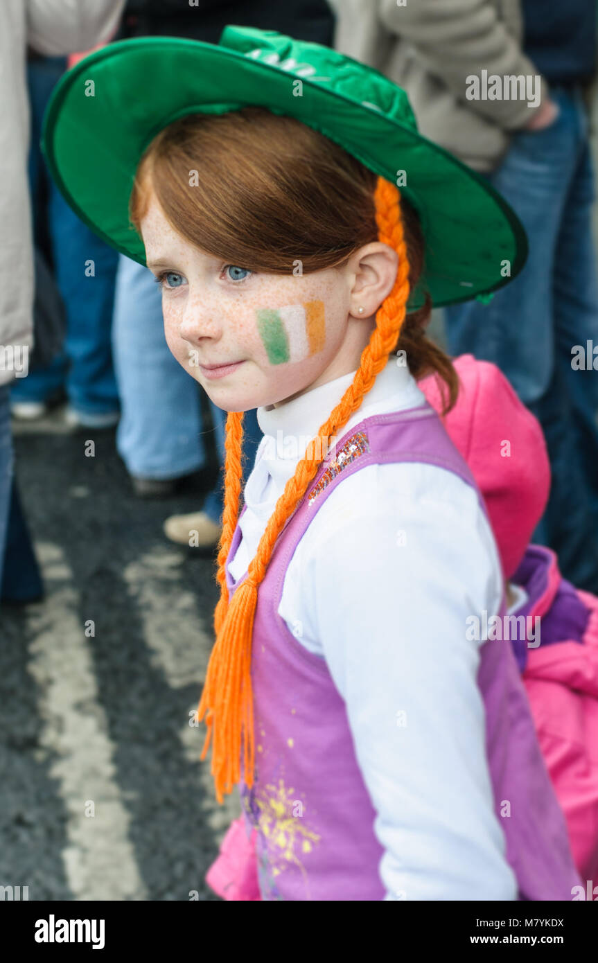 A girl in a hat with her face painted in the colours of the Irish flag ...