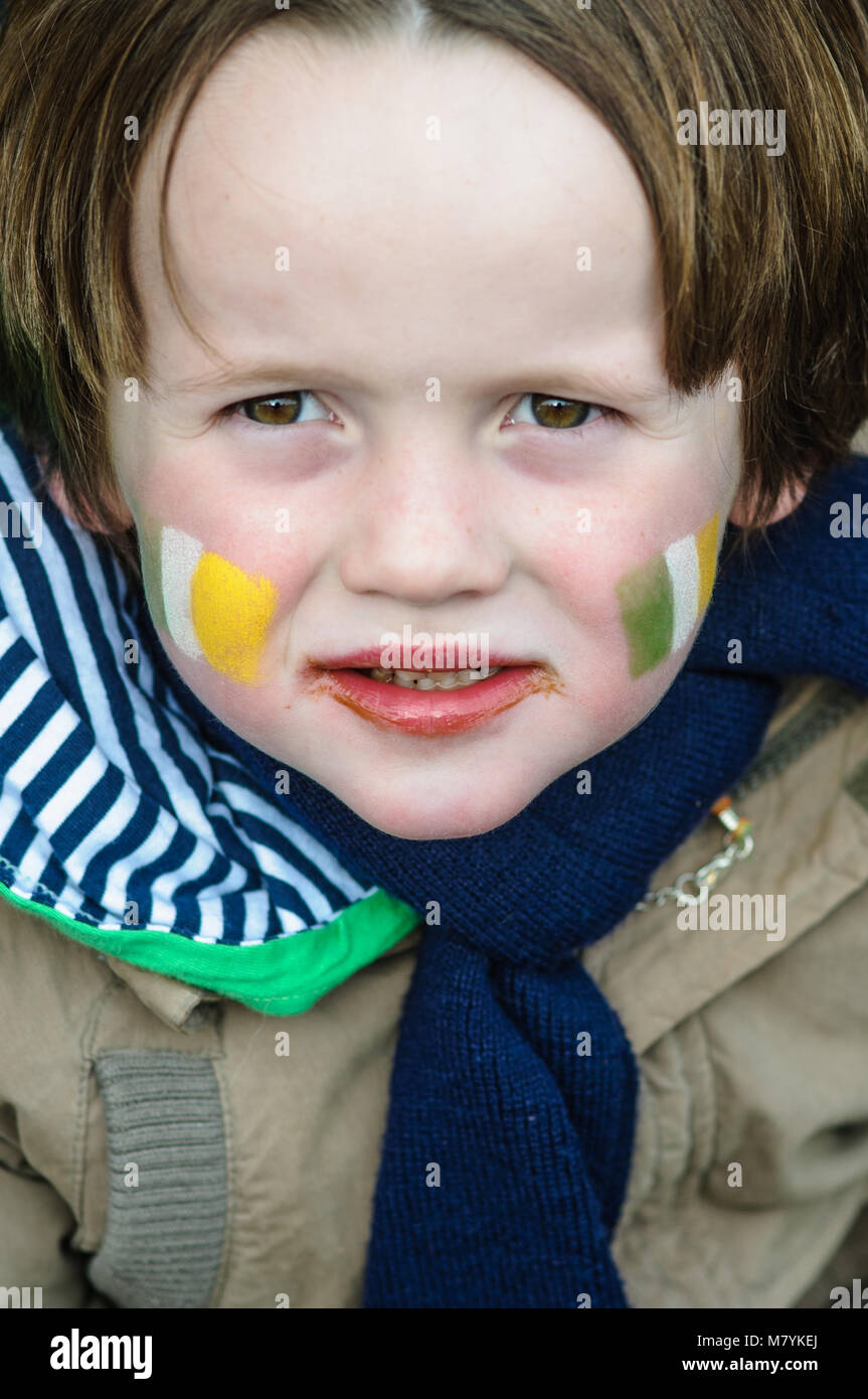 A boy with his face painted in the colours of the Irish flag is ...