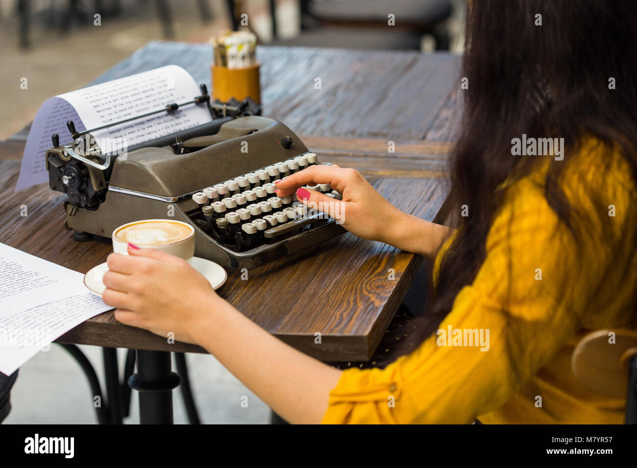 Cropped shot of a female writer's hands typing on a retro typewriter ...