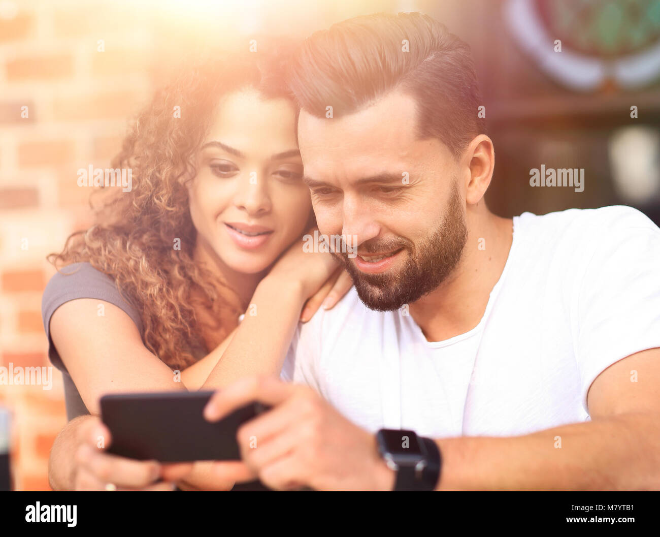 Happy smiling couple using a smartphone sitting in terrace Stock Photo ...
