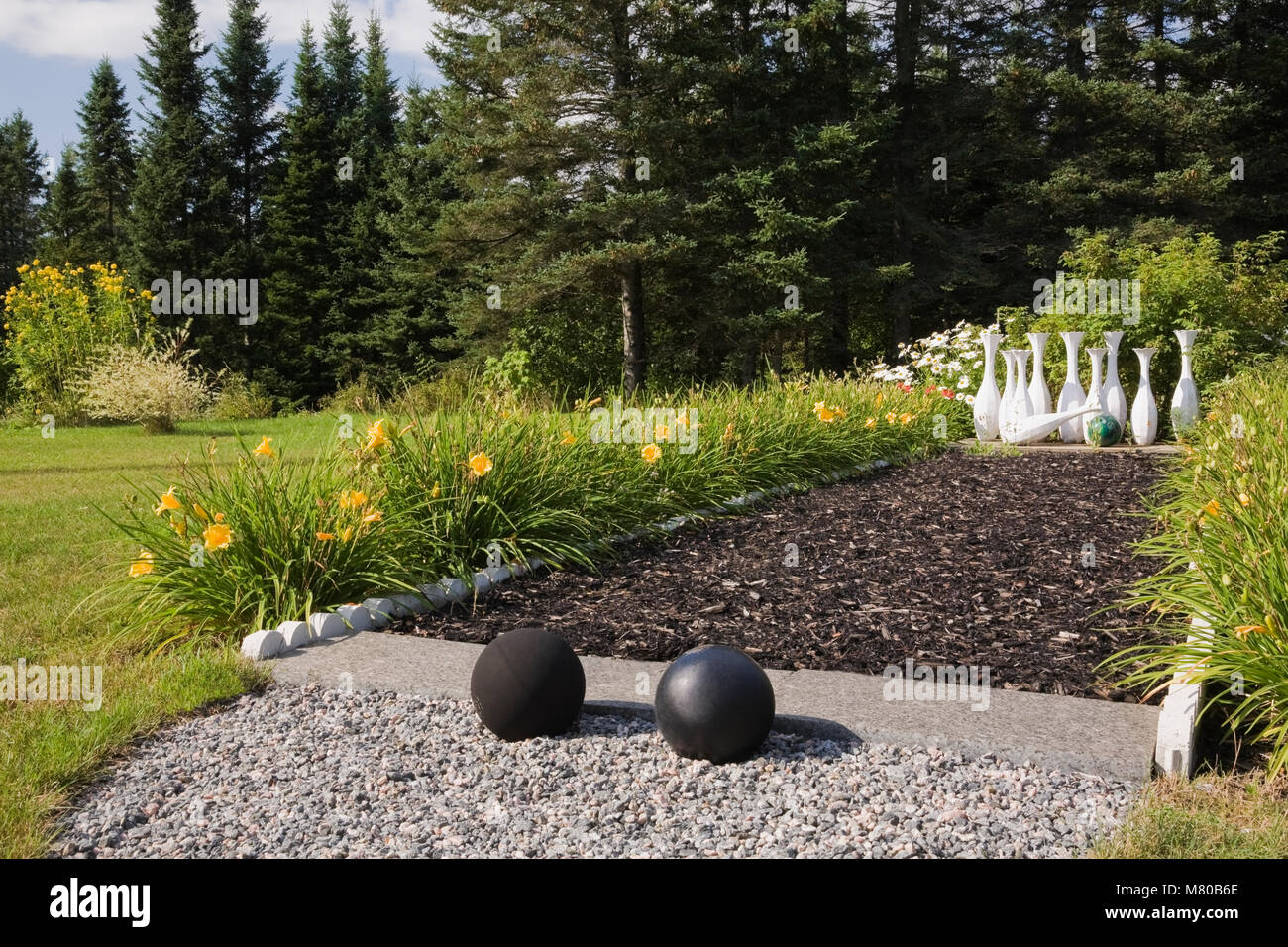 Black bowling balls and mulch alley with concrete bowling pins in a ...