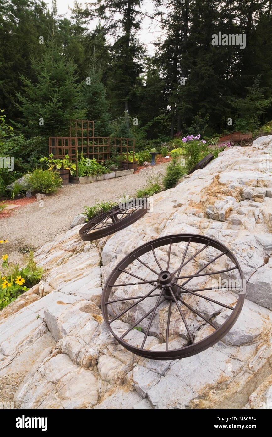 Wagon wheels on top of a large rock surface in a landscaped front yard ...