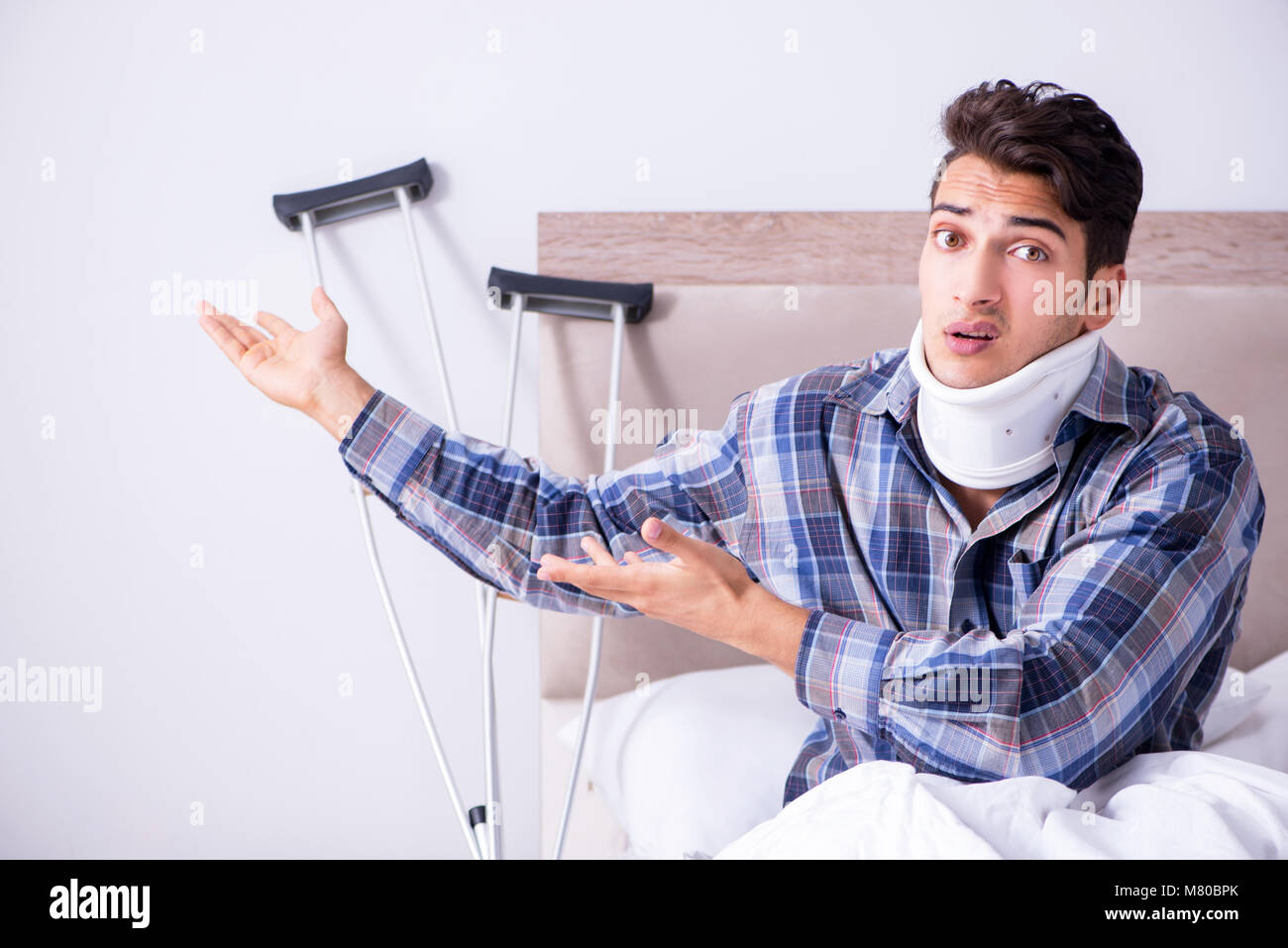 Injured man in bed at home with crutches hi-res stock photography and ...