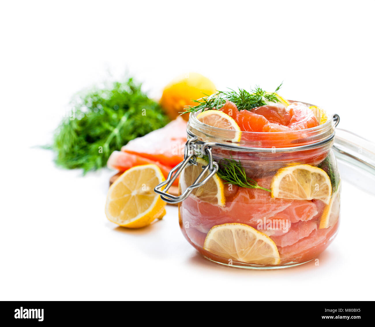 Salted salmon with lemon in glass jar isolated on white background ...