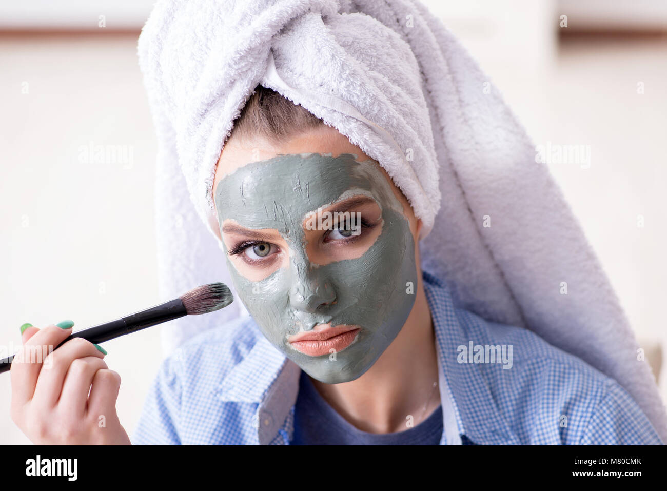Woman applying clay mask with brush at home Stock Photo - Alamy