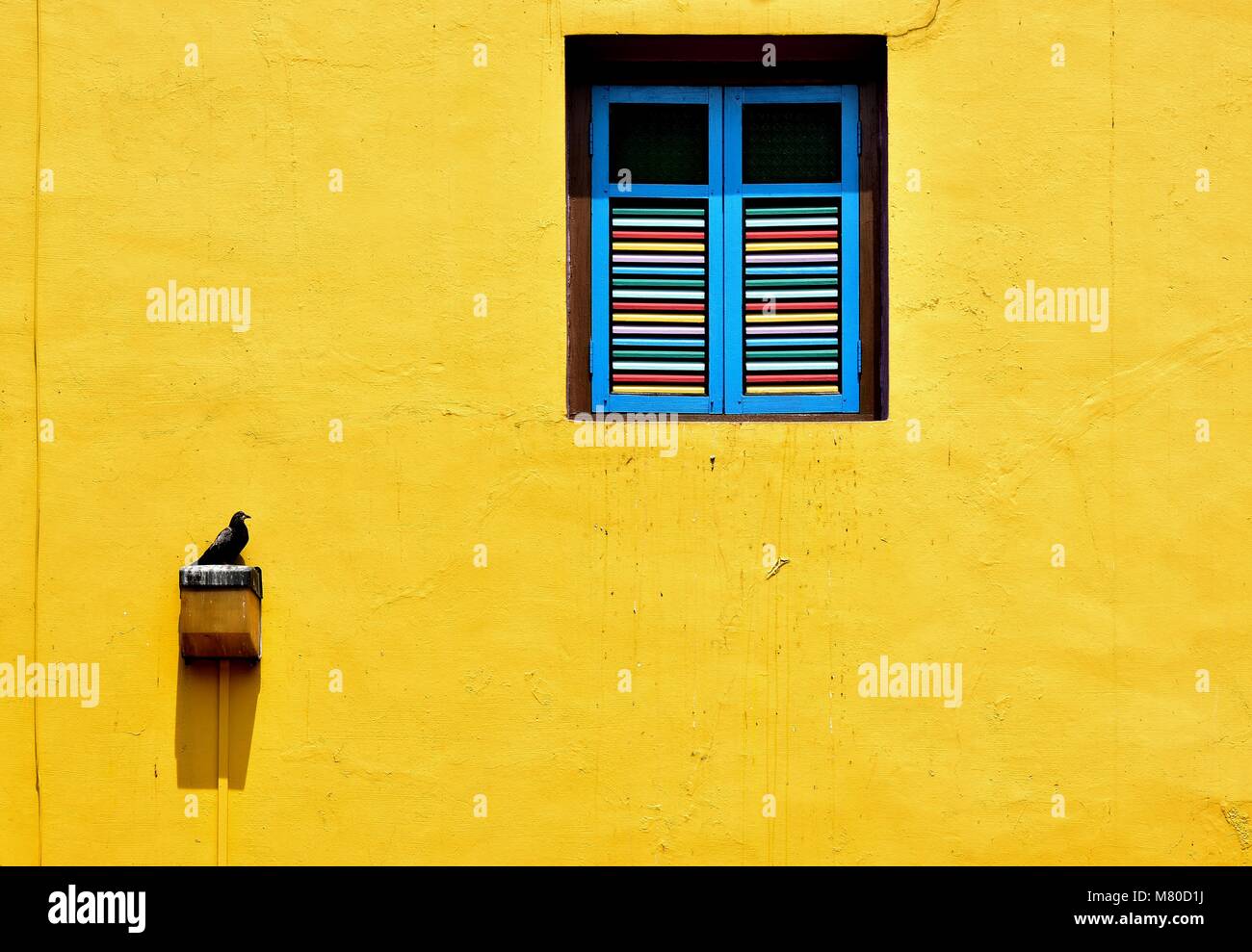 Colorful antique window with shutters on bright yellow wall of a ...