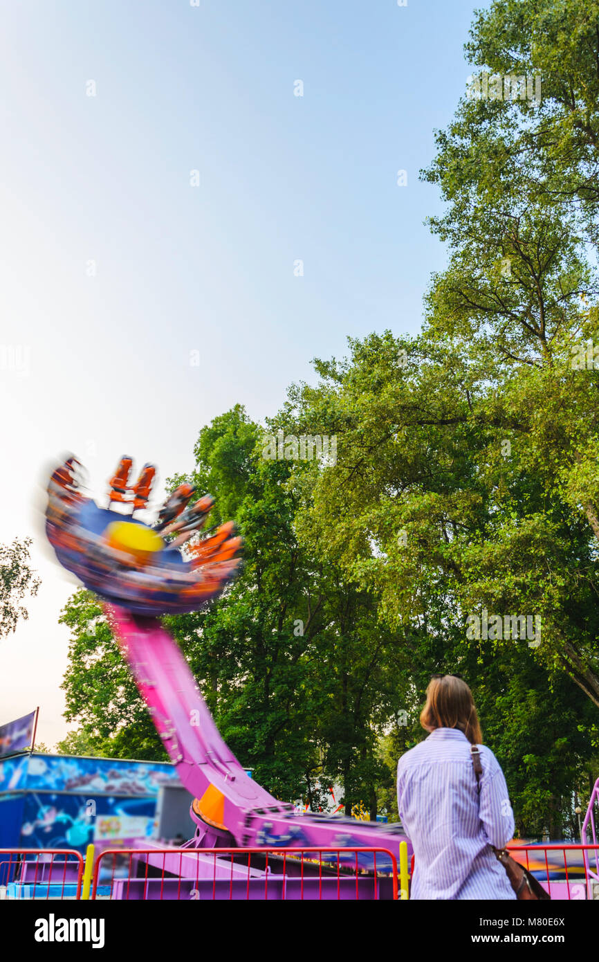 Young Girl Looks at a Fast-Rotation Amusement Ride in Amusement Park ...